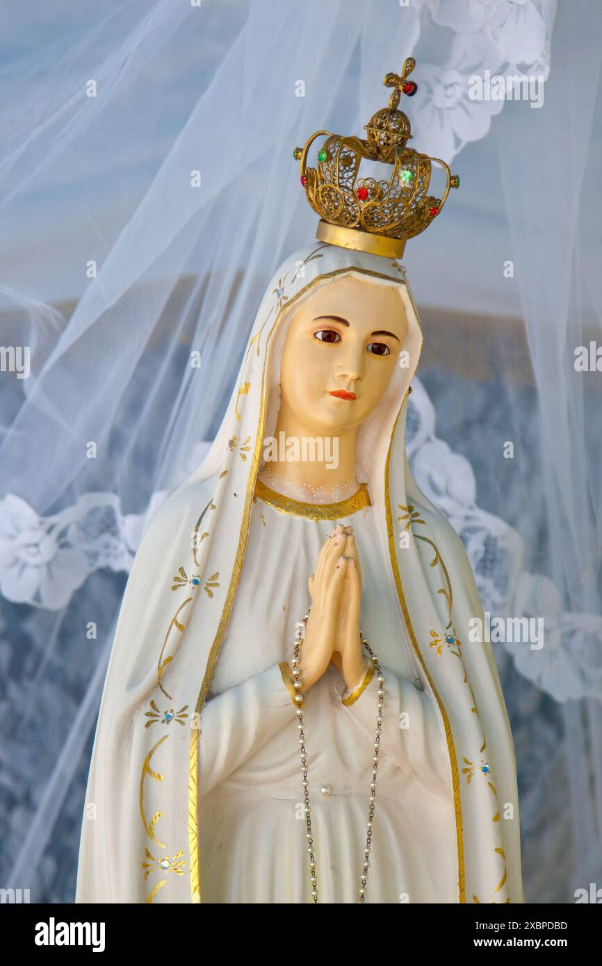 Statue of the virgin mary in a peaceful pose, adorned with a golden ...