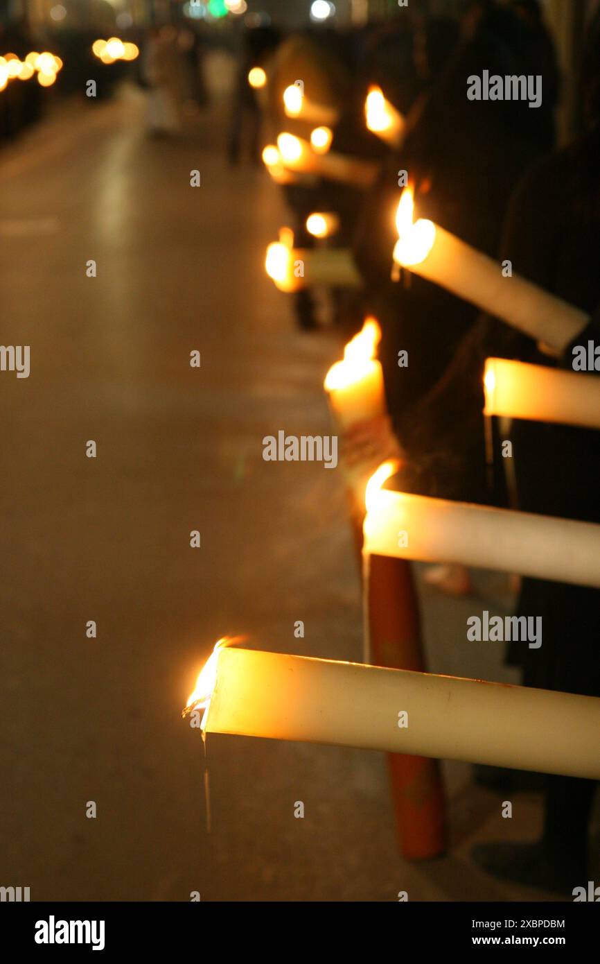 Row of people holding big burning candles during a night religious ...