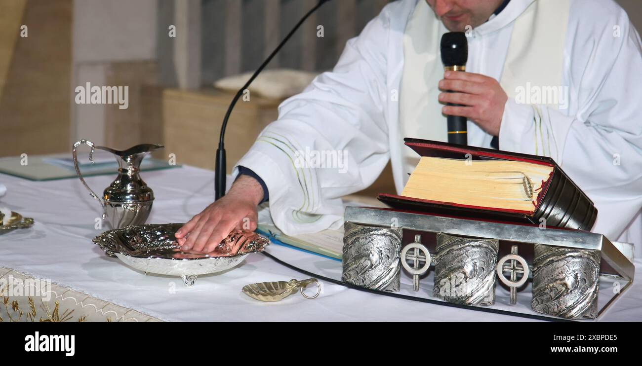 Priest preparing for a baptism ceremony, holding a microphone and ...