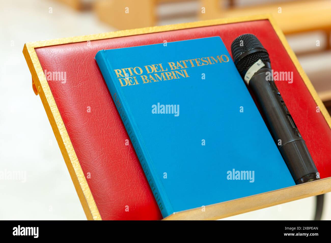 Blue book for the rite of baptism and a microphone laying on a red and ...