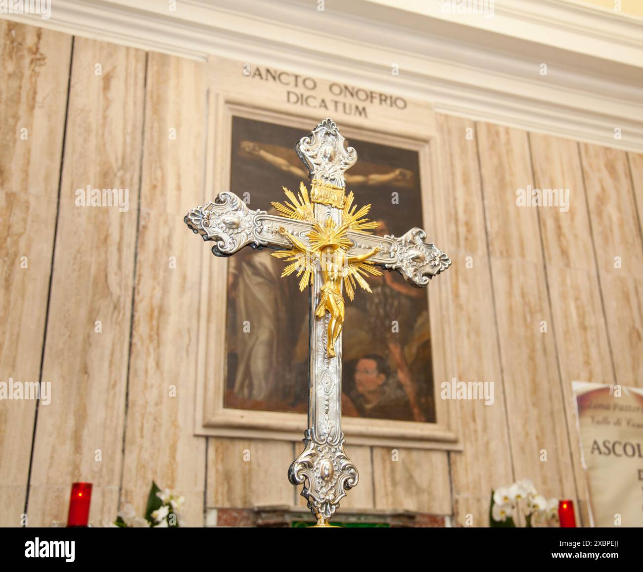 Silver and gold crucifix standing in a church with a painting depicting ...