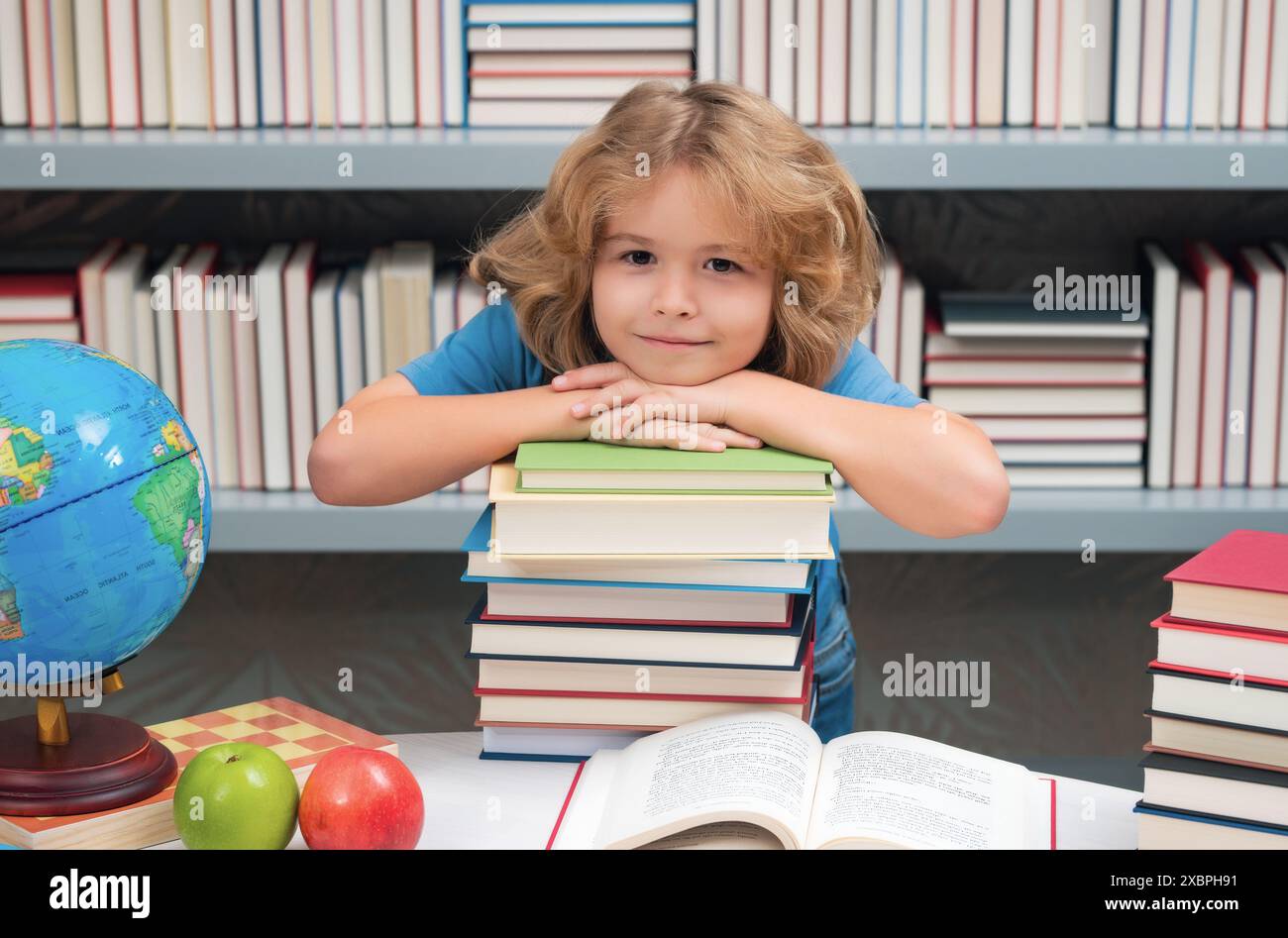 School boy with stack of books in library. School child. Kid boy from ...