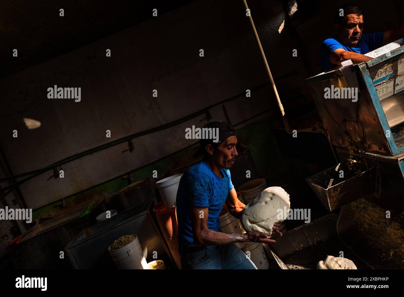 Mexican workers operate a corn mill to produce dough for making ...