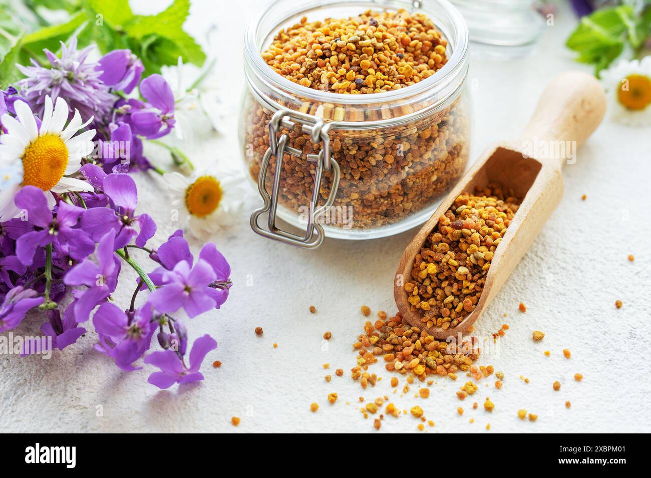 Healthy bee pollen grains. Bee pollen on a glass jar and wild flowers ...