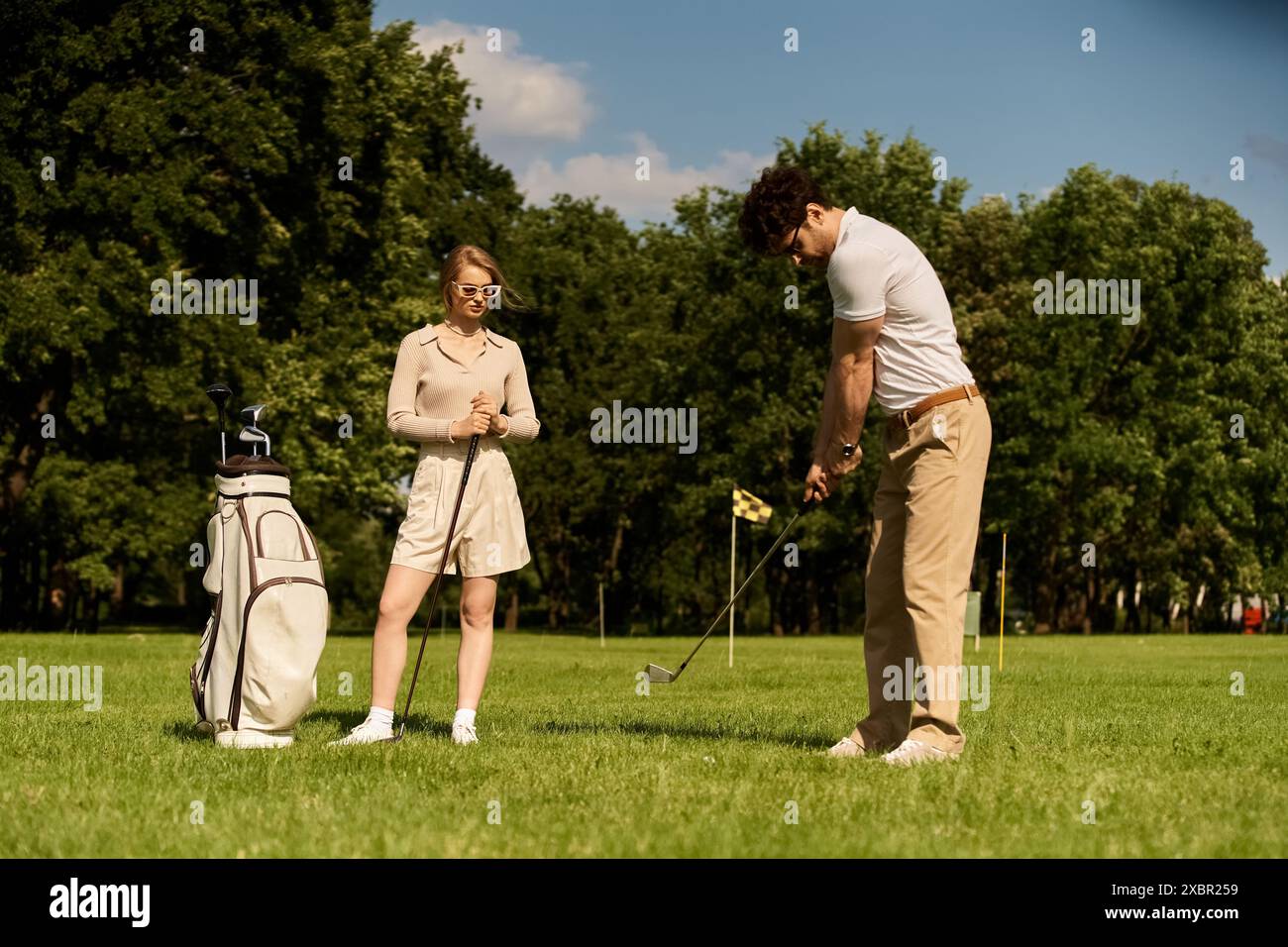A young couple in elegant attire enjoys a game of golf on a lush green ...