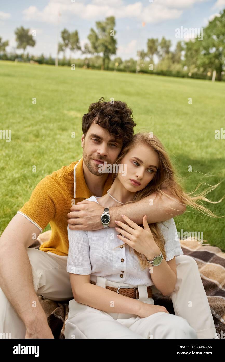 A beautiful young couple in elegant attire relaxes on a blanket in a ...
