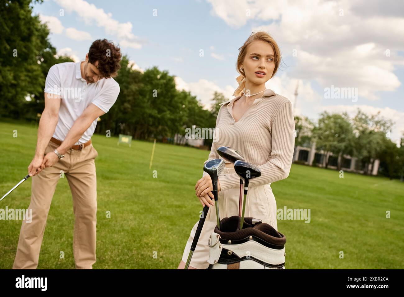 A young couple in elegant attire playing golf together on a green field ...