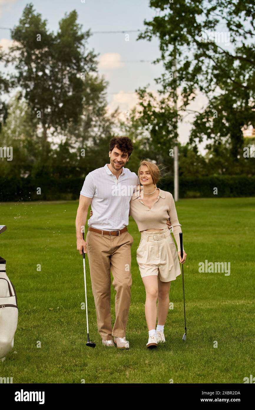 A stylish young couple leisurely walking across a golf course, basking ...