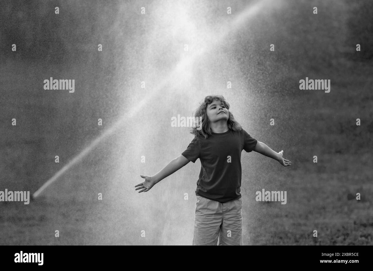 Kid play in garden near irrigation watering sprinkler system. Watering ...