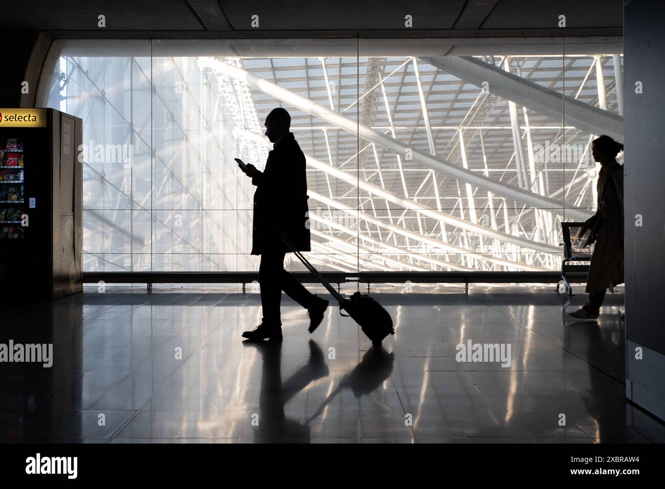 A silhouette of a business traveller with his lugage walking to catch ...