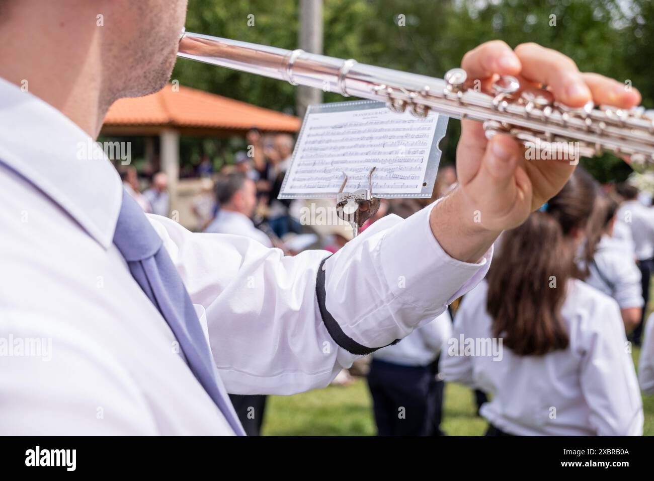 Musician playing the transverse flute with a band at an outdoor concert ...