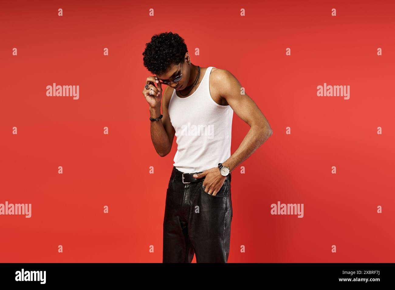 Handsome African American man in white tank top and leather pants with ...