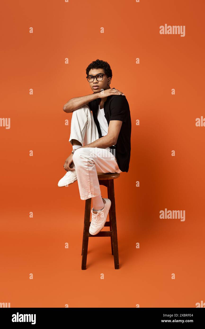 A handsome African American man sits on a stool in front of a bright ...
