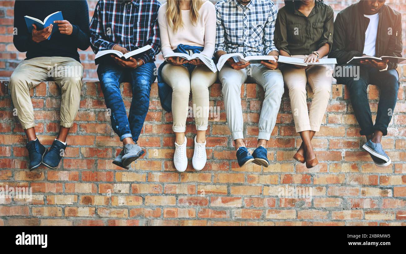 Students, group and books on wall with legs, learning and reading for ...