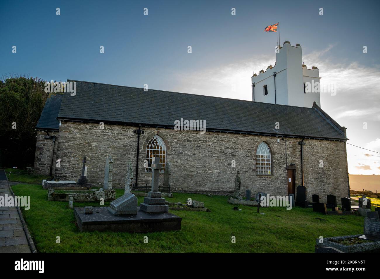 A tattered Union Jack flag flies against a blue sky from the tower at ...