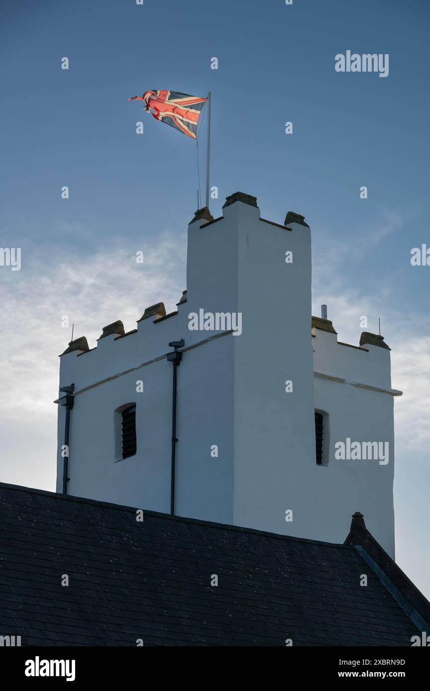 A tattered Union Jack flag flies against a blue sky from the tower at ...