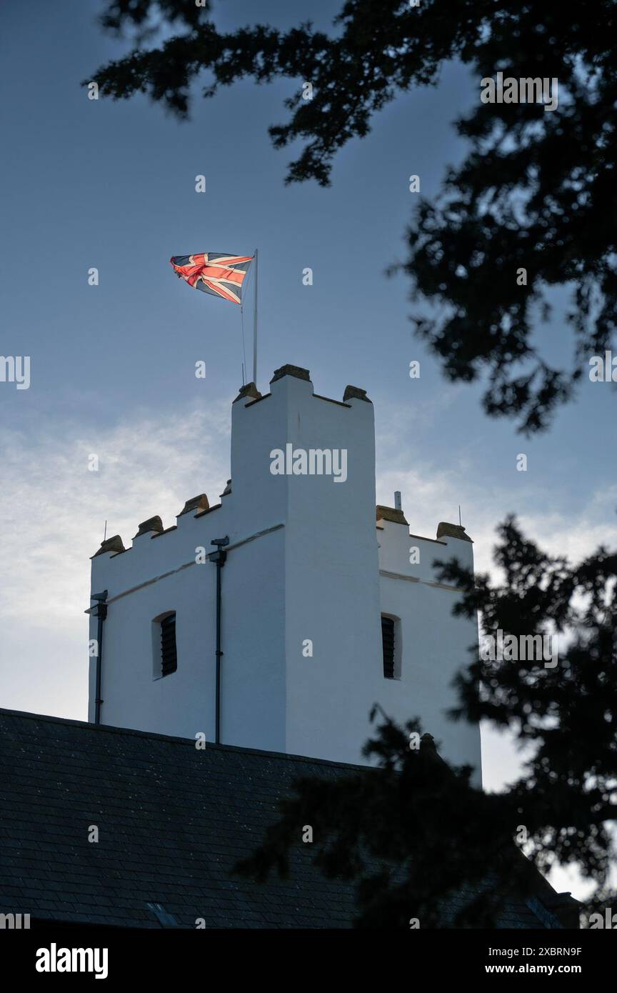 A tattered Union Jack flag flies against a blue sky from the tower at ...