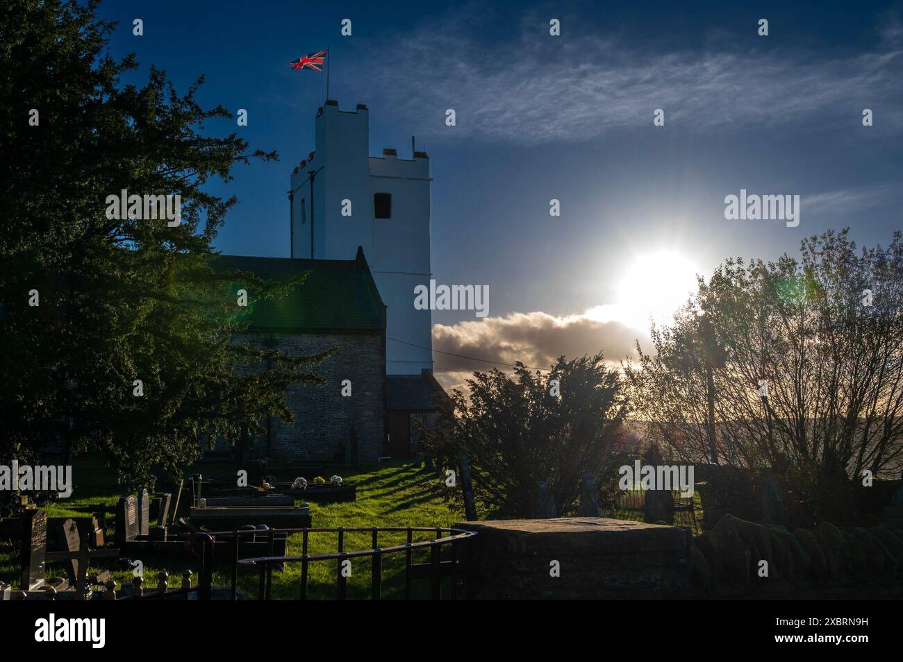 A tattered Union Jack flag flies against a blue sky from the tower at ...