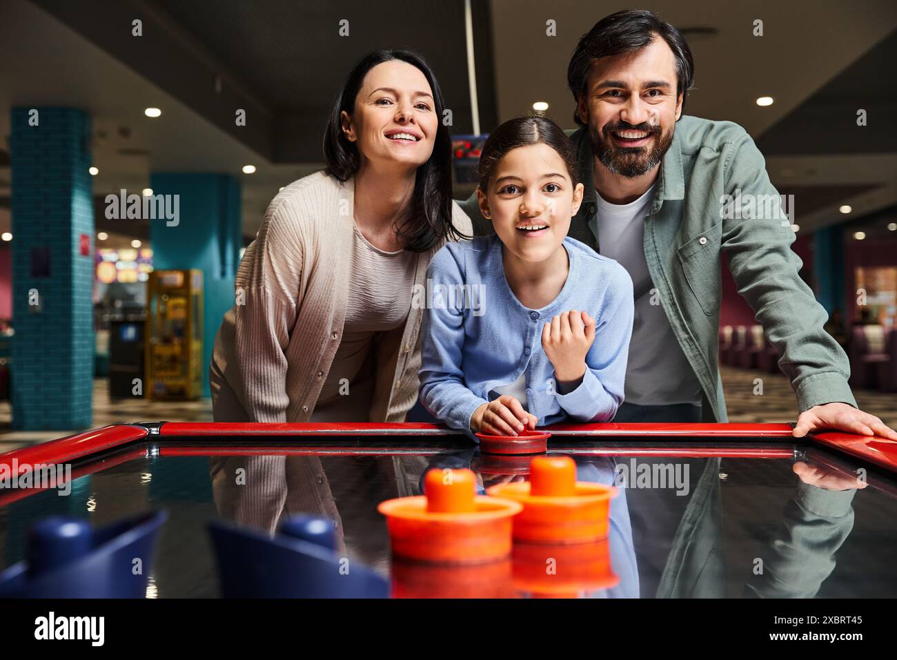 A happy family enjoys a game of billiards in an arcade during the ...