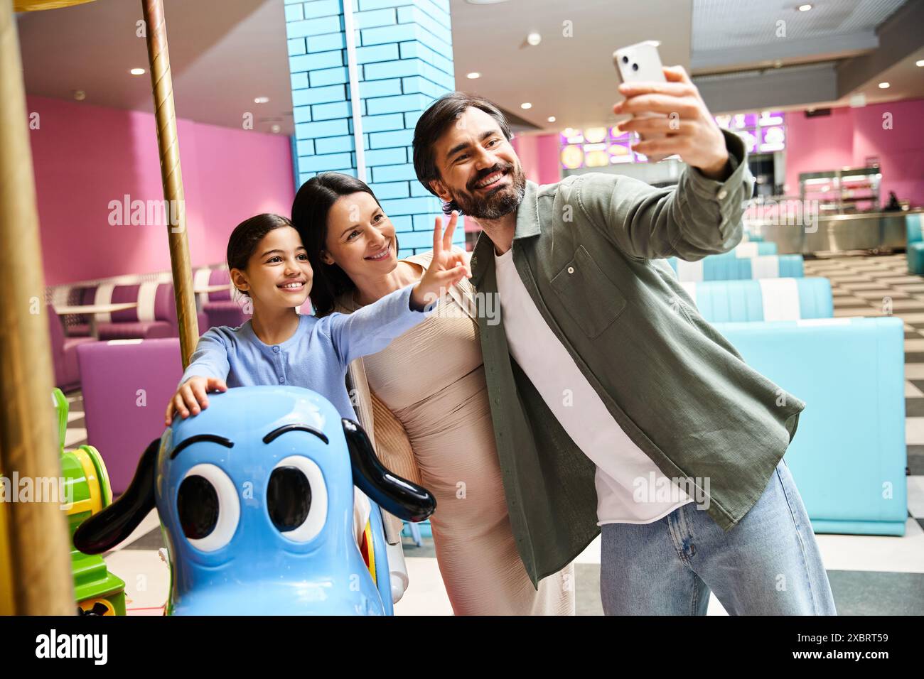 A joyful family smiles while taking a selfie in front of a carousel toy ...