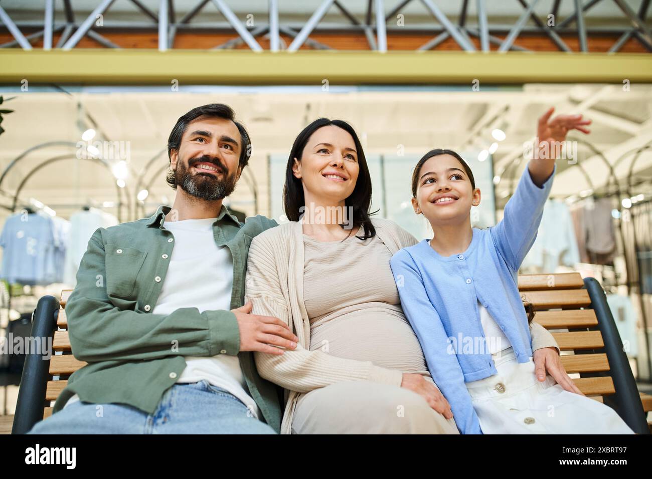 A joyful family with kids sitting together on a bench in a busy ...