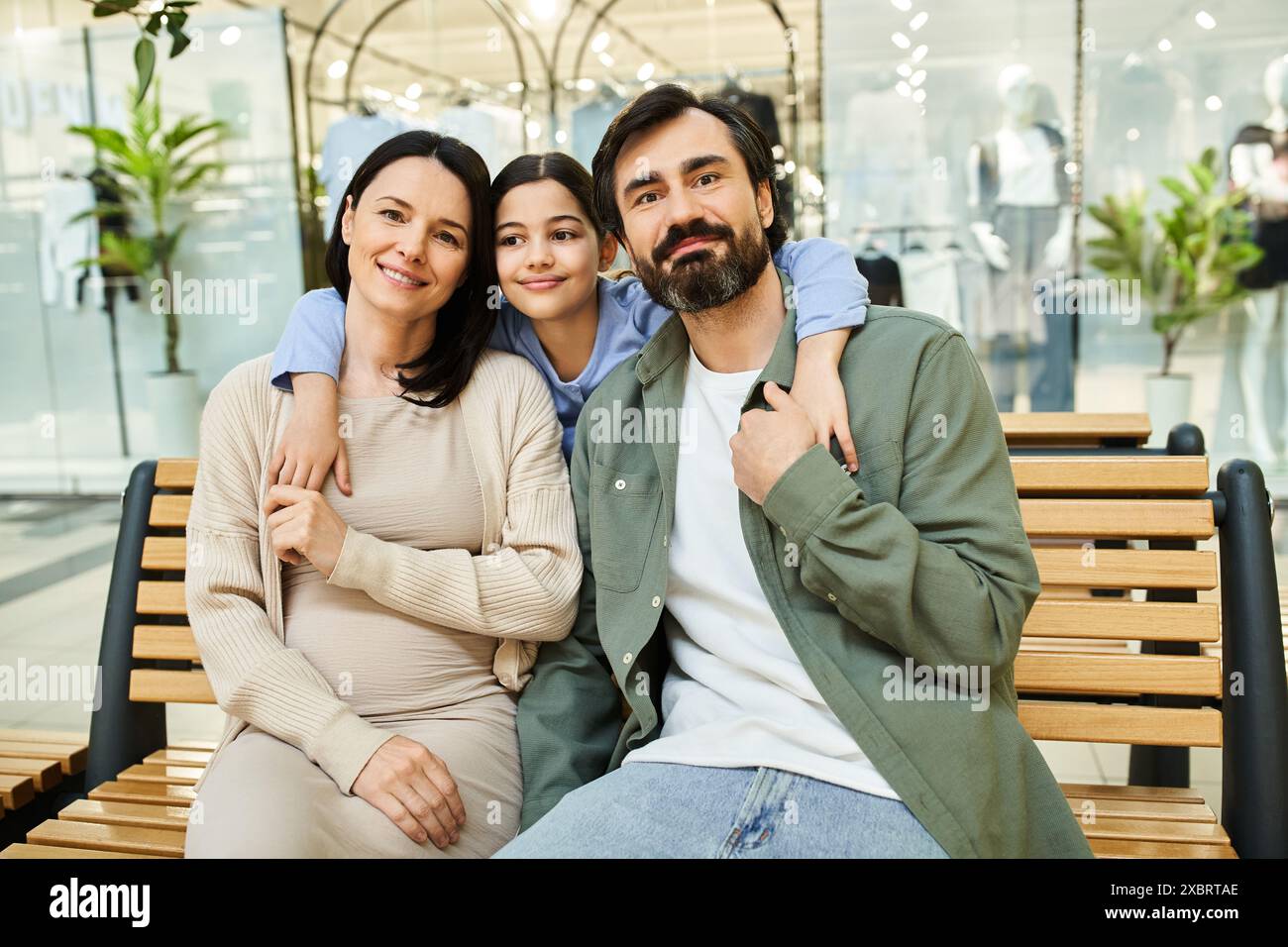 A joyful family relaxes on a bench in a busy shopping mall, enjoying a ...