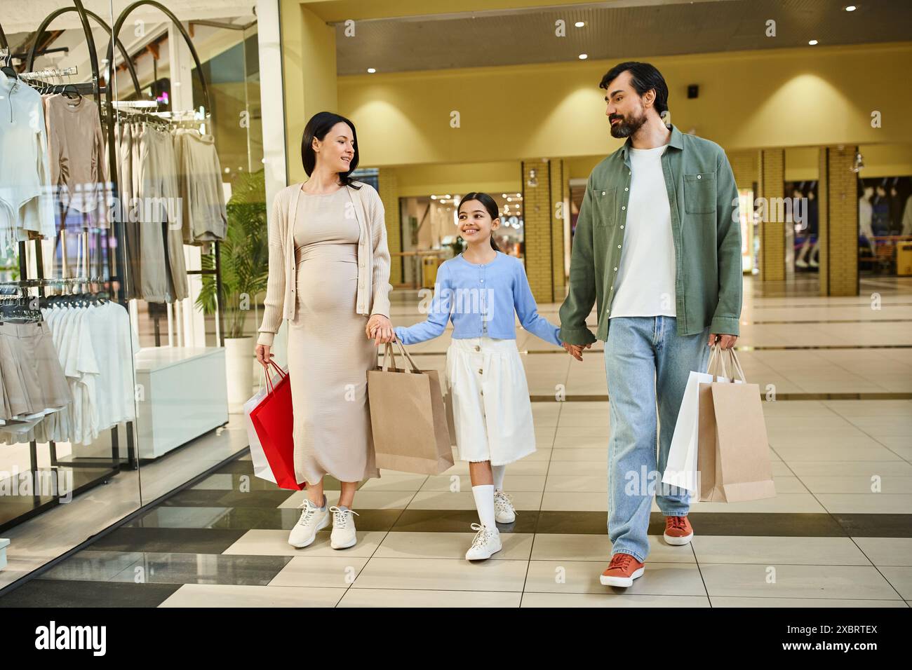 A happy family enjoying a shopping weekend, walking through a busy mall ...