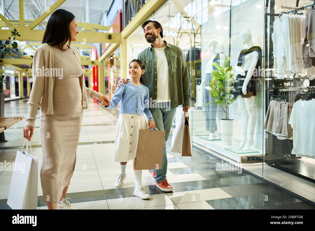 A joyful family explores a shopping mall, browsing and shopping ...