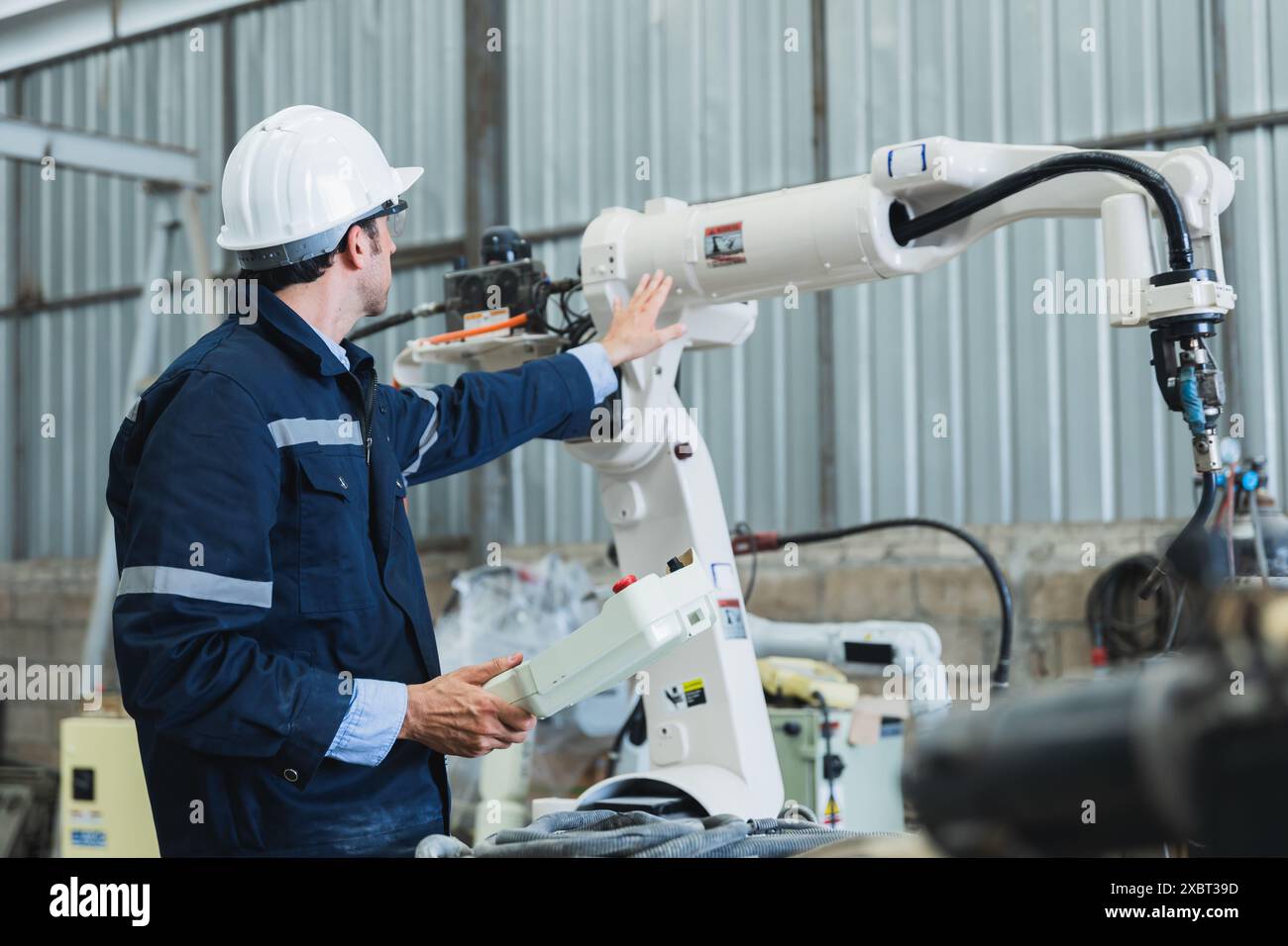 engineer controlling robot arm at factory. checking the operation of ...