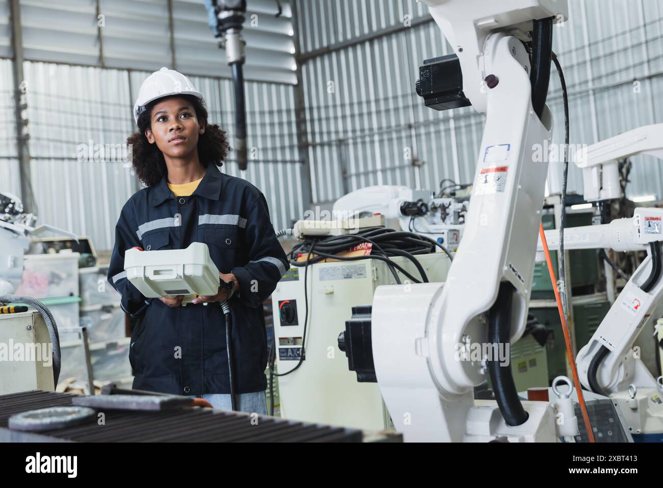 engineer controlling robot arm at factory. checking the operation of ...
