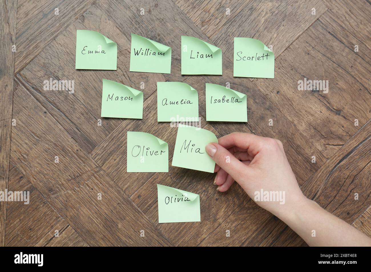 Woman holding paper sticker with name at wooden table, top view ...