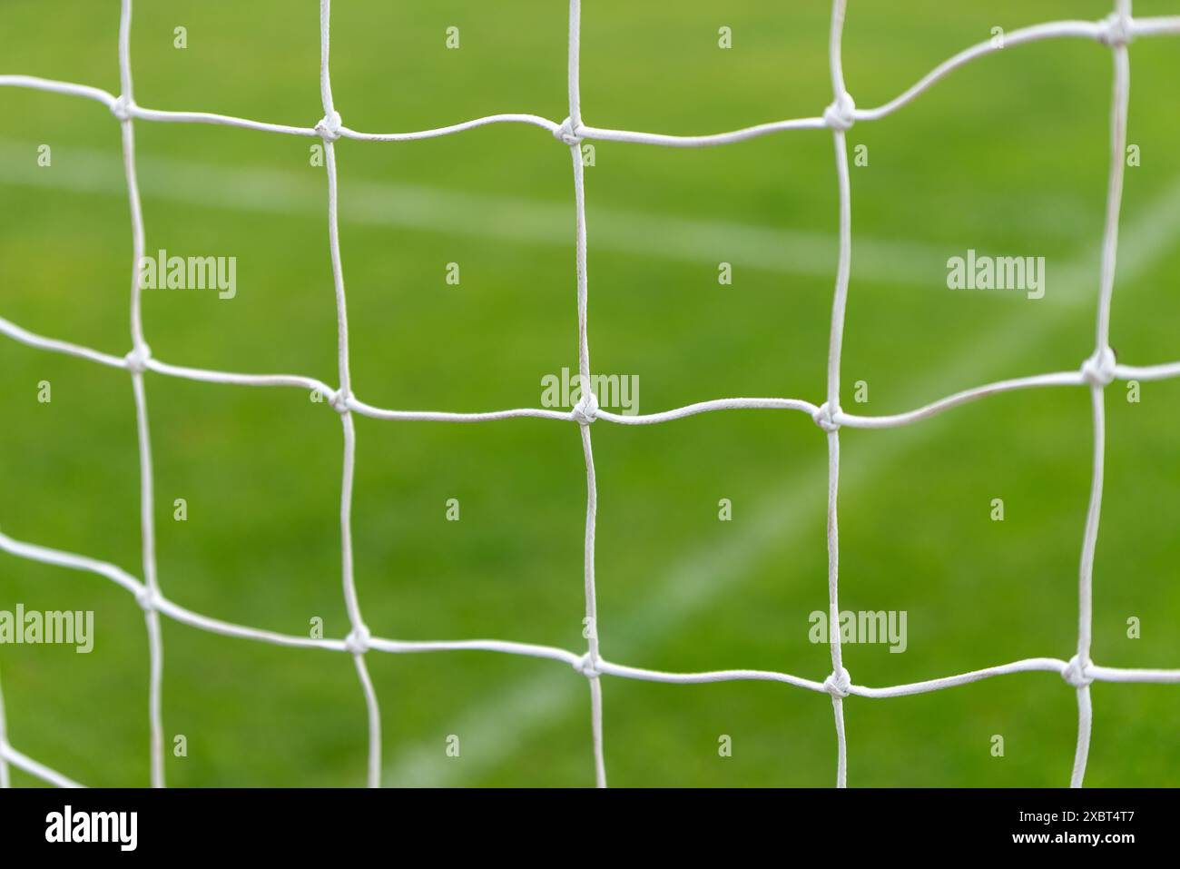 Close-up shot of a goal net with green grass and field lines in the ...