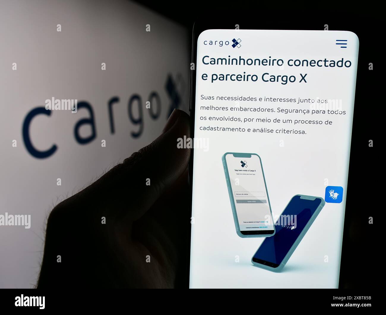 Person holding cellphone with webpage of Brazilian logistics platform company CargoX in front of ...