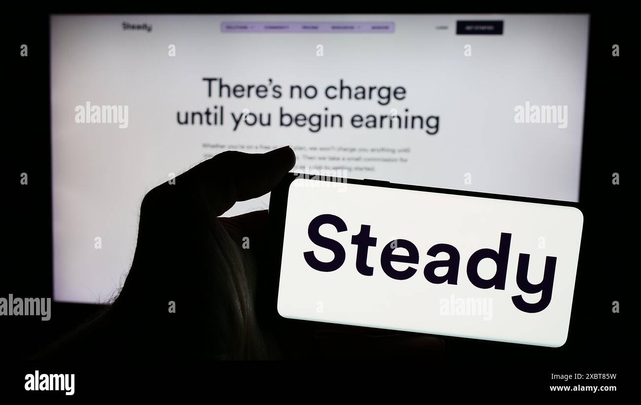 Person holding mobile phone with logo of German crowdfunding company Steady Media GmbH in front ...