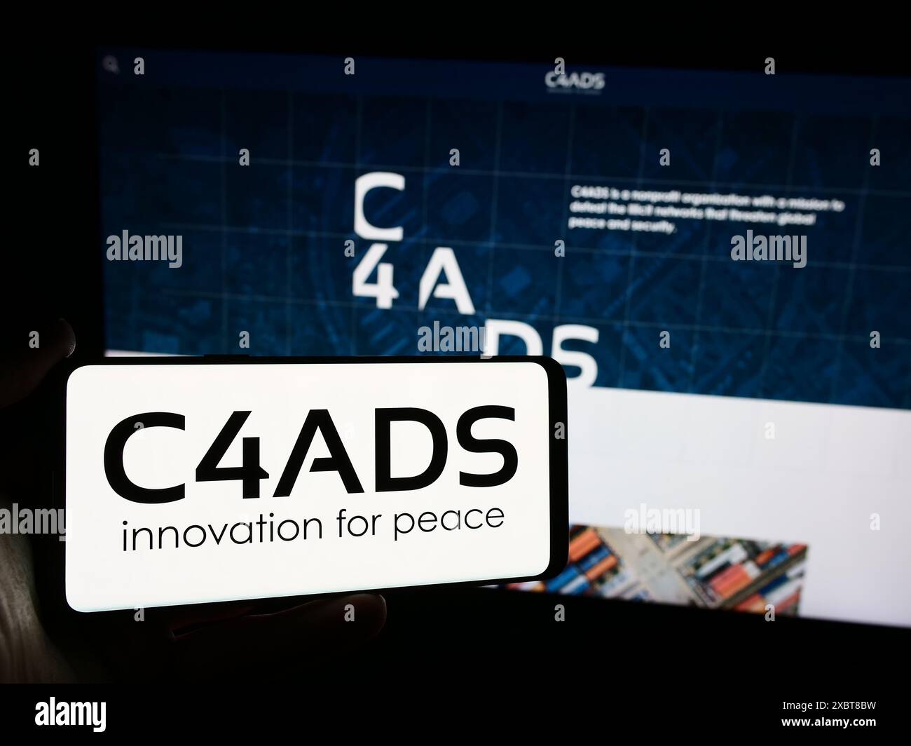 Person holding mobile phone with logo of Center for Advanced Defense Studies (C4ADS) in front of ...