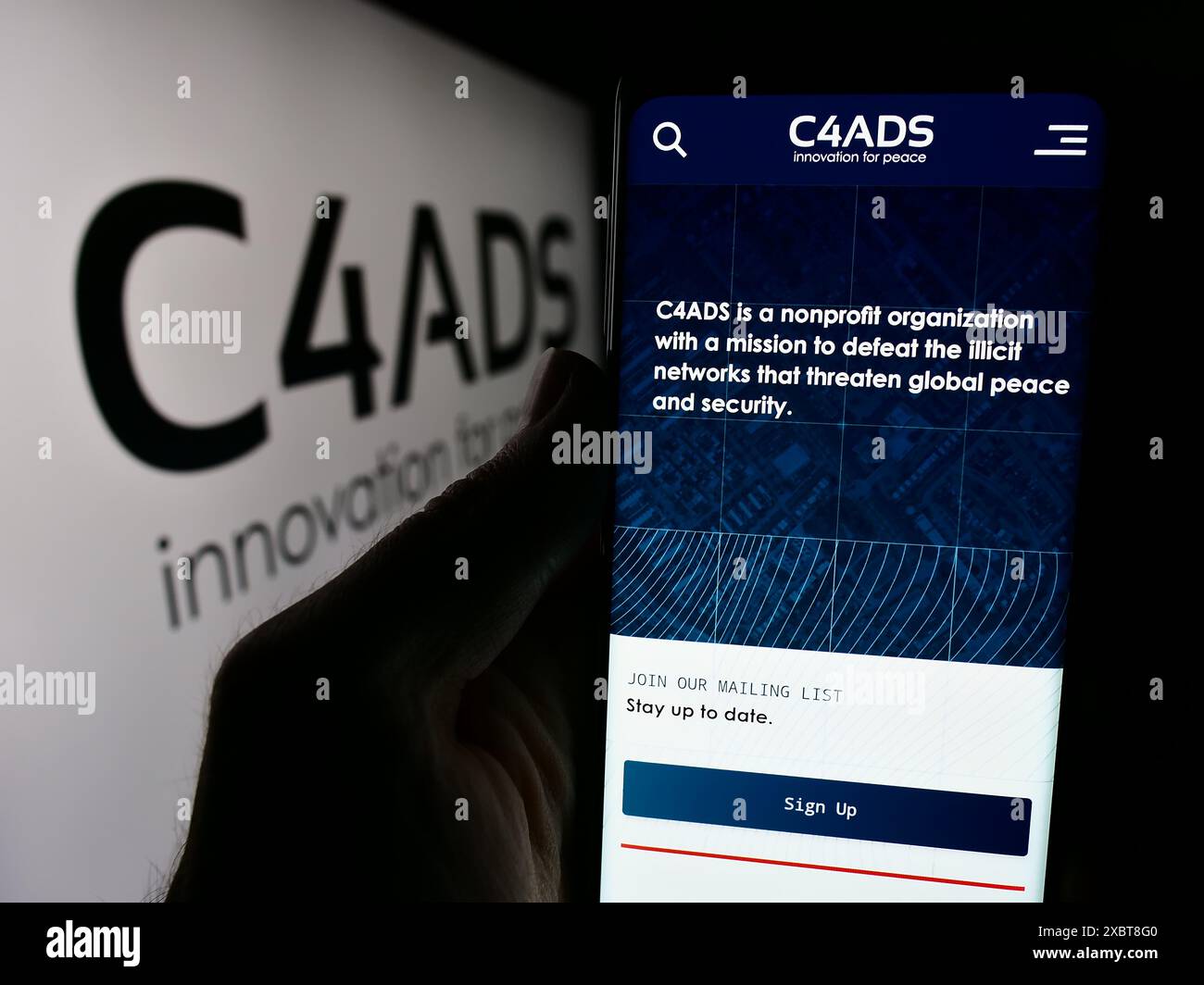 Person holding cellphone with webpage of Center for Advanced Defense Studies (C4ADS) in front of ...
