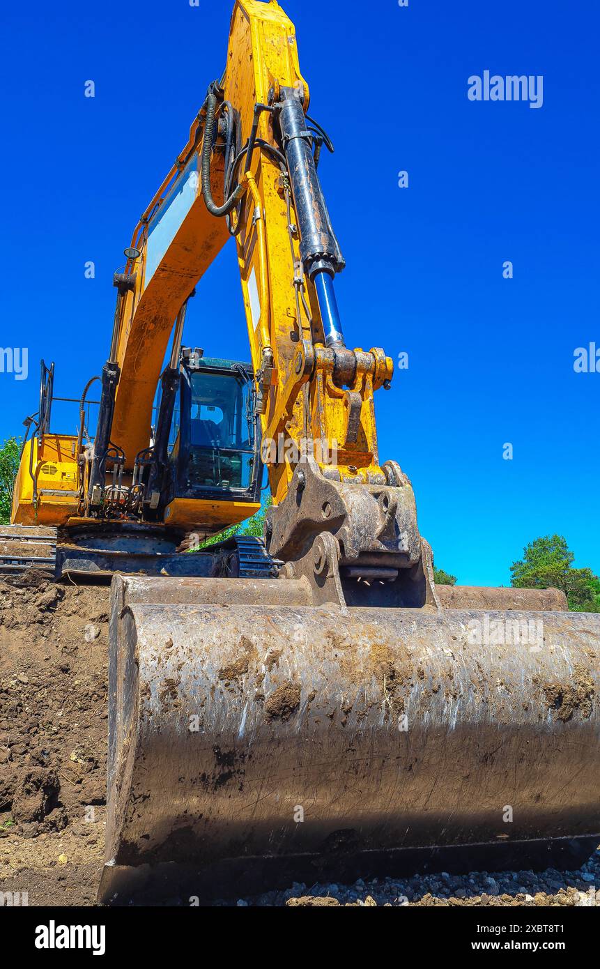 Side view of yellow excavator bucket against blue sky. Close. Excavator ...