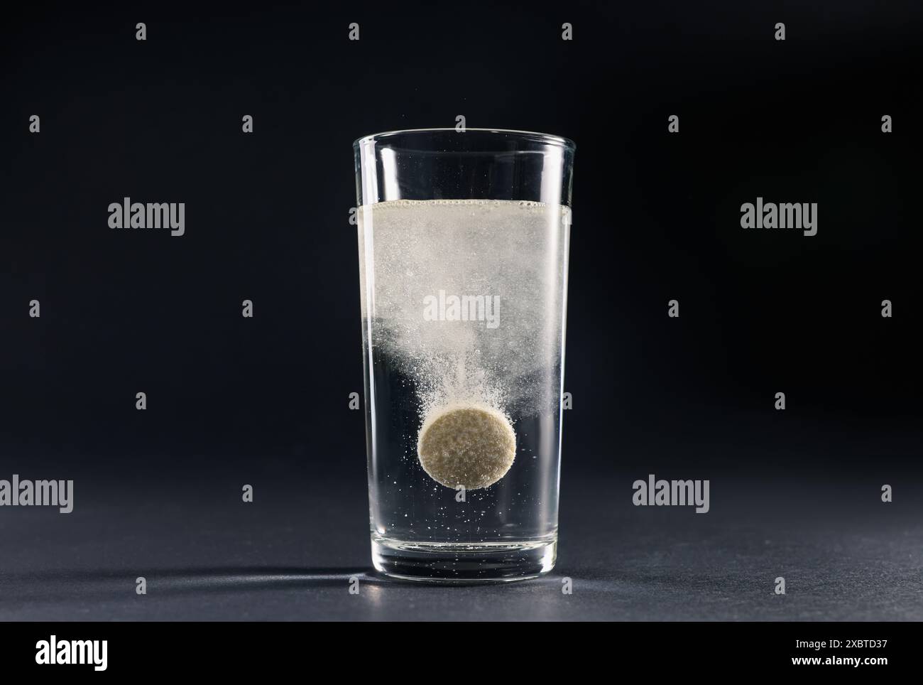 Effervescent pill dissolving in glass of water on grey table Stock ...