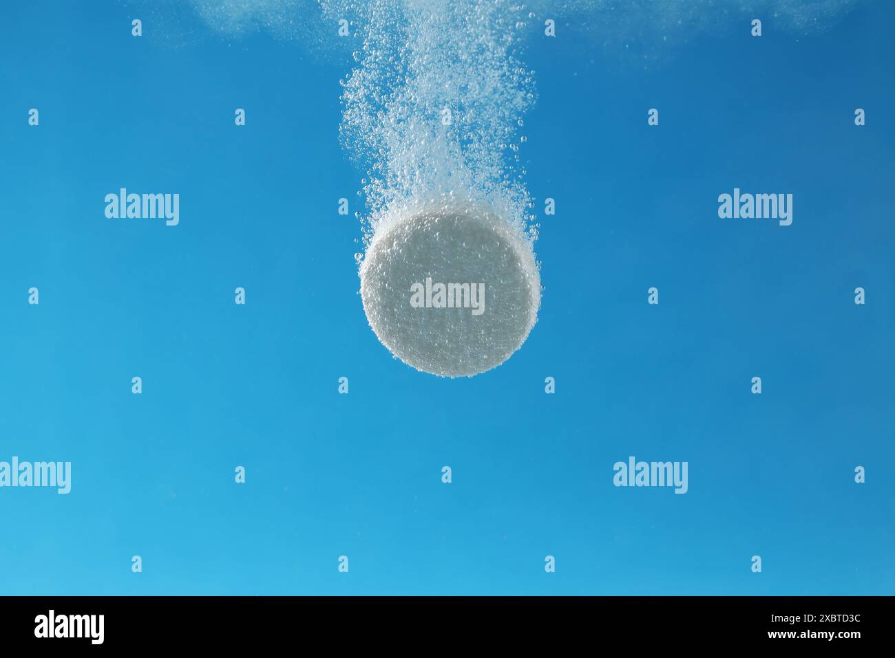 Effervescent pill dissolving in water on light blue background, closeup ...