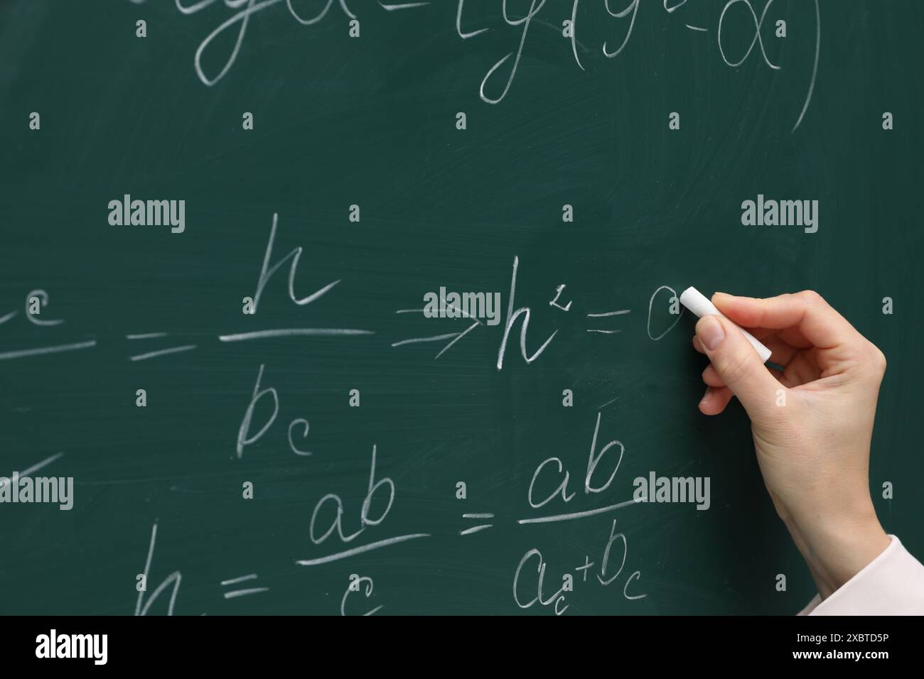 Teacher writing down math equation on green board, closeup Stock Photo ...