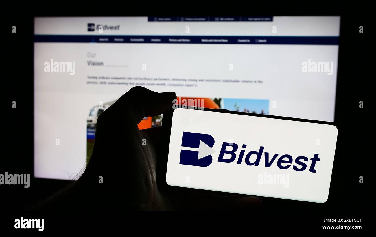 Person holding mobile phone with logo of South African conglomerate ...