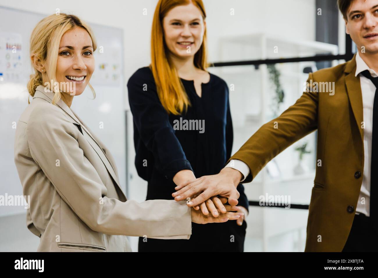 Multiethnic work team put their hands together as a sign of group union ...