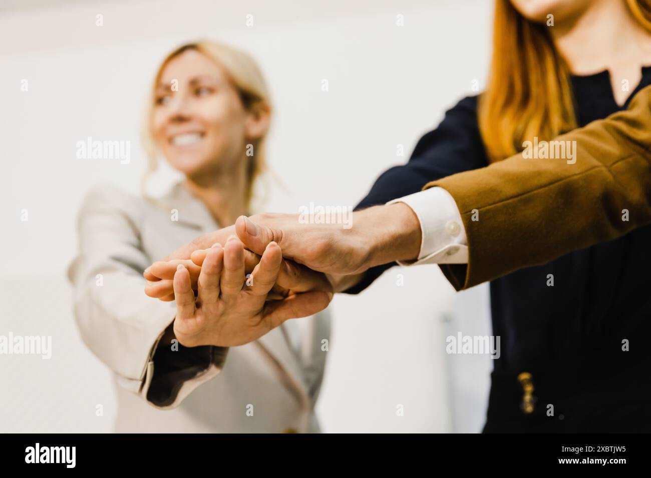 Multiethnic work team put their hands together as a sign of group union ...