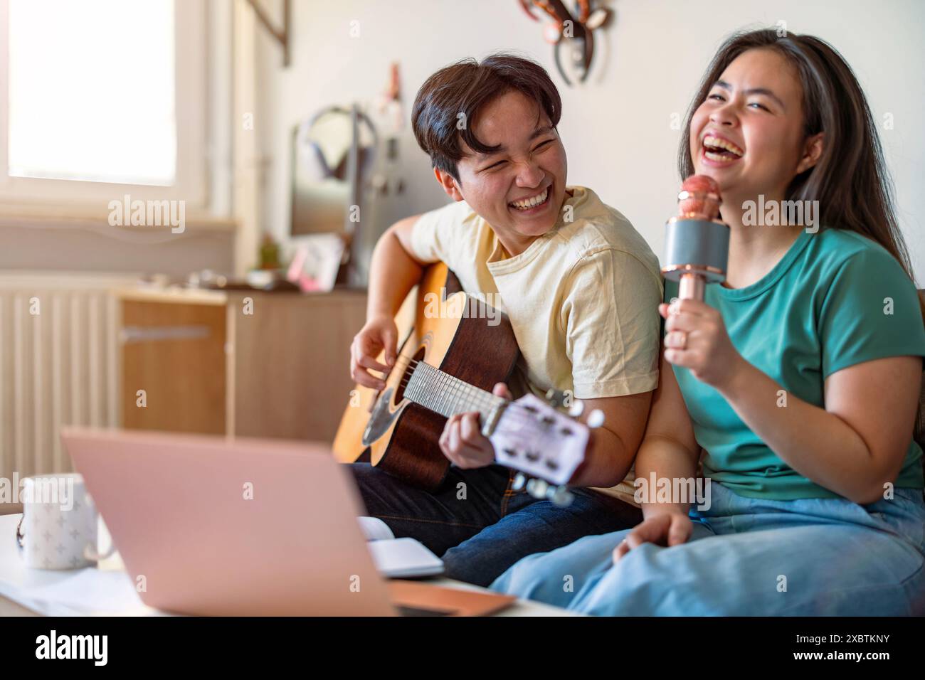 Happy young couple singing and playing the guitar at home Stock Photo ...