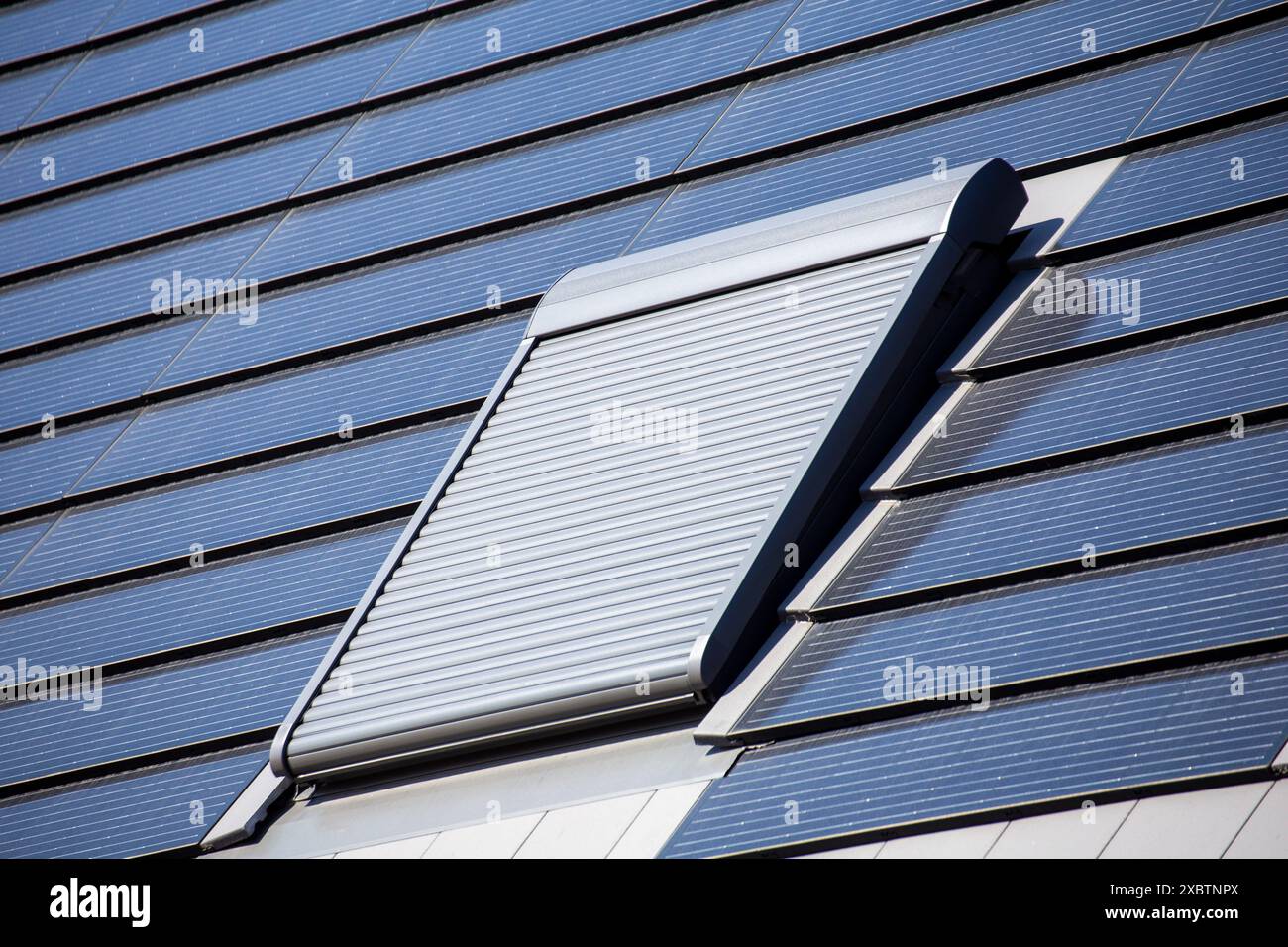 Roof window with roller shutter on a detached house with photovoltaic ...