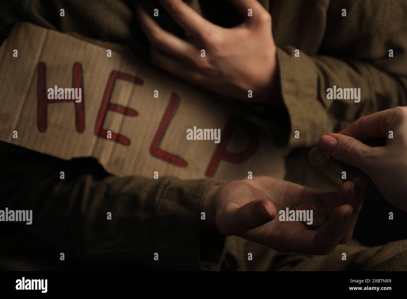 Woman giving coins to homeless with help sign, closeup. Charity and ...