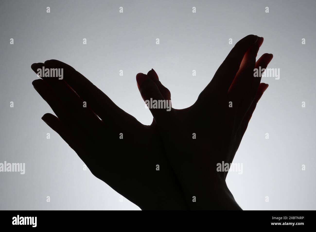 Shadow puppet. Woman making hand gesture like bird on grey background ...