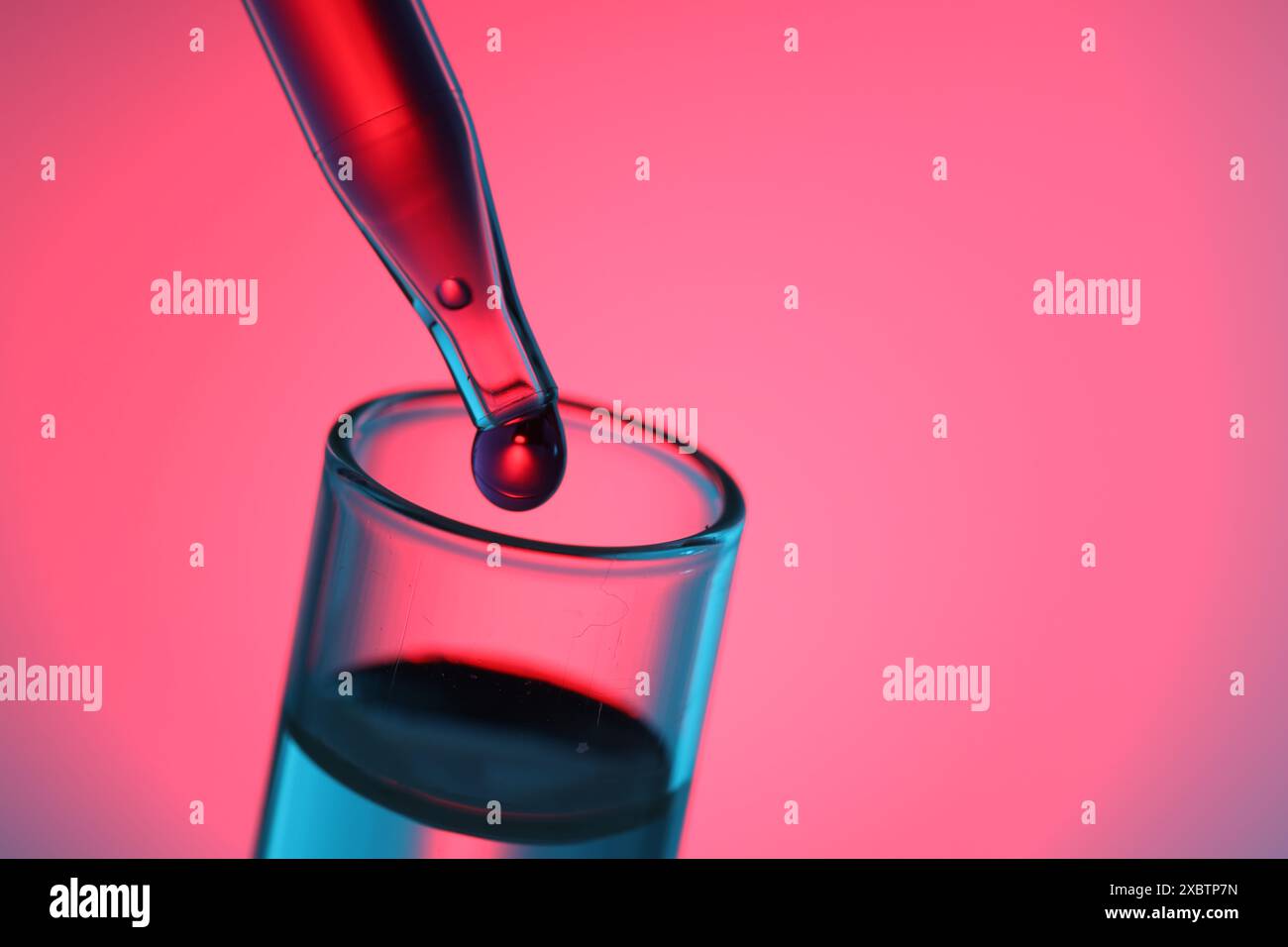 Dripping liquid from pipette into test tube on color background ...