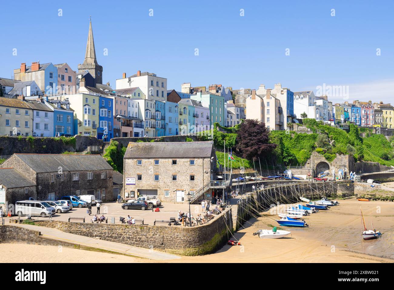 Tenby Harbour with small boats moored low tide with Tenby colourful ...