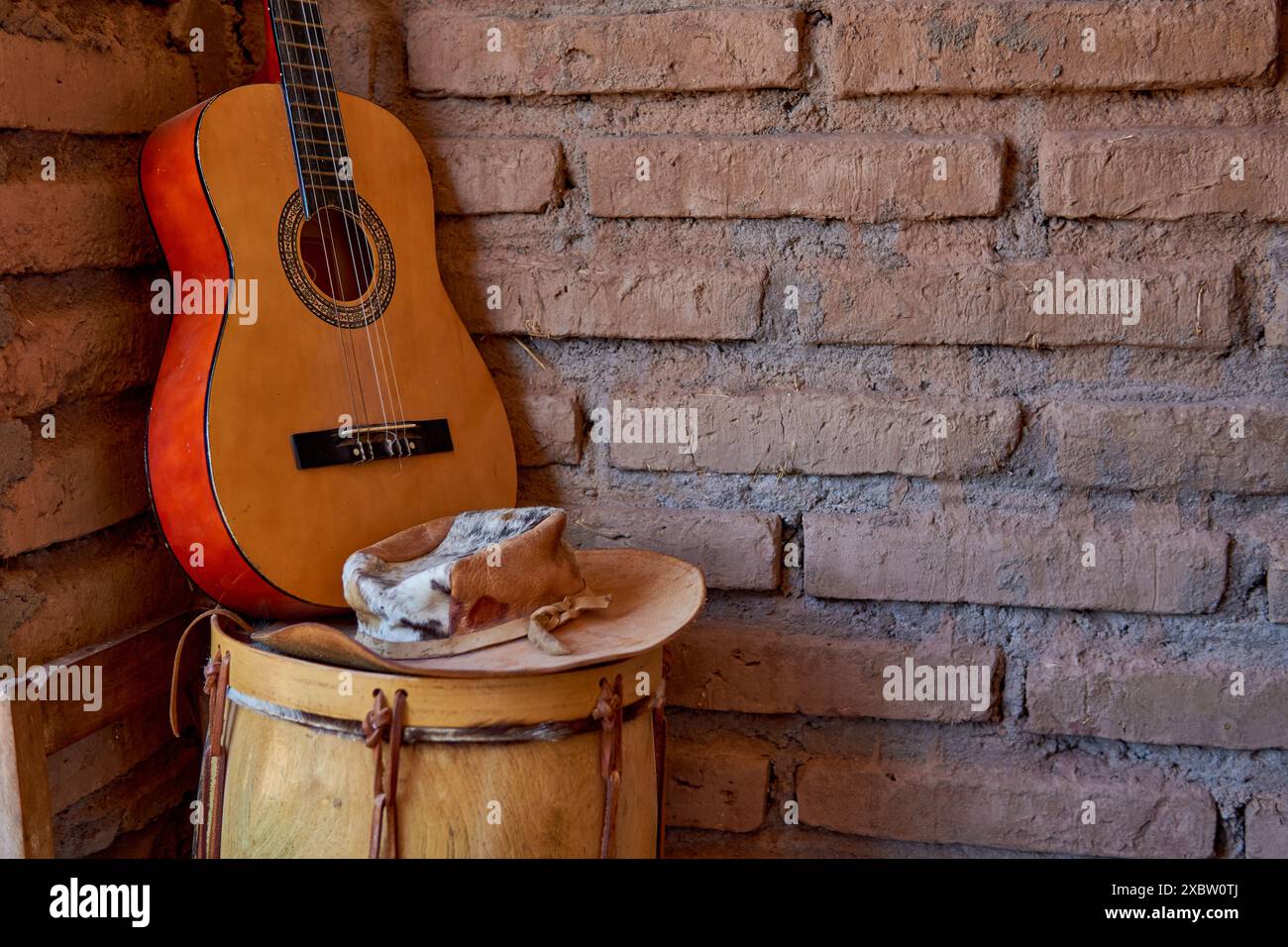 classic criollo guitar on display on top of a drum and a hat, in the ...